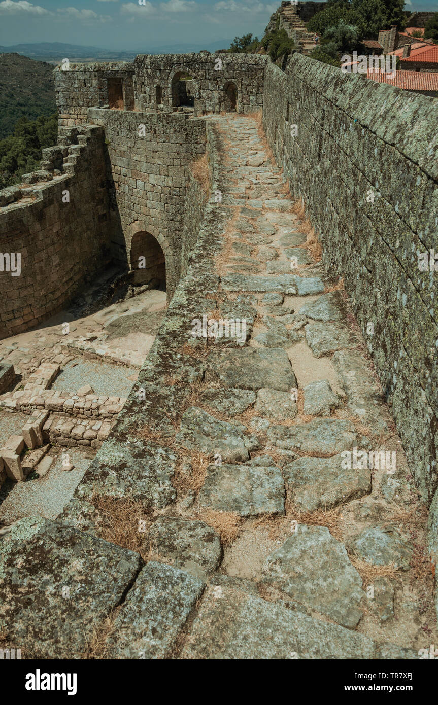 Pathway on stone wall with front gate and hilly landscape at the ...