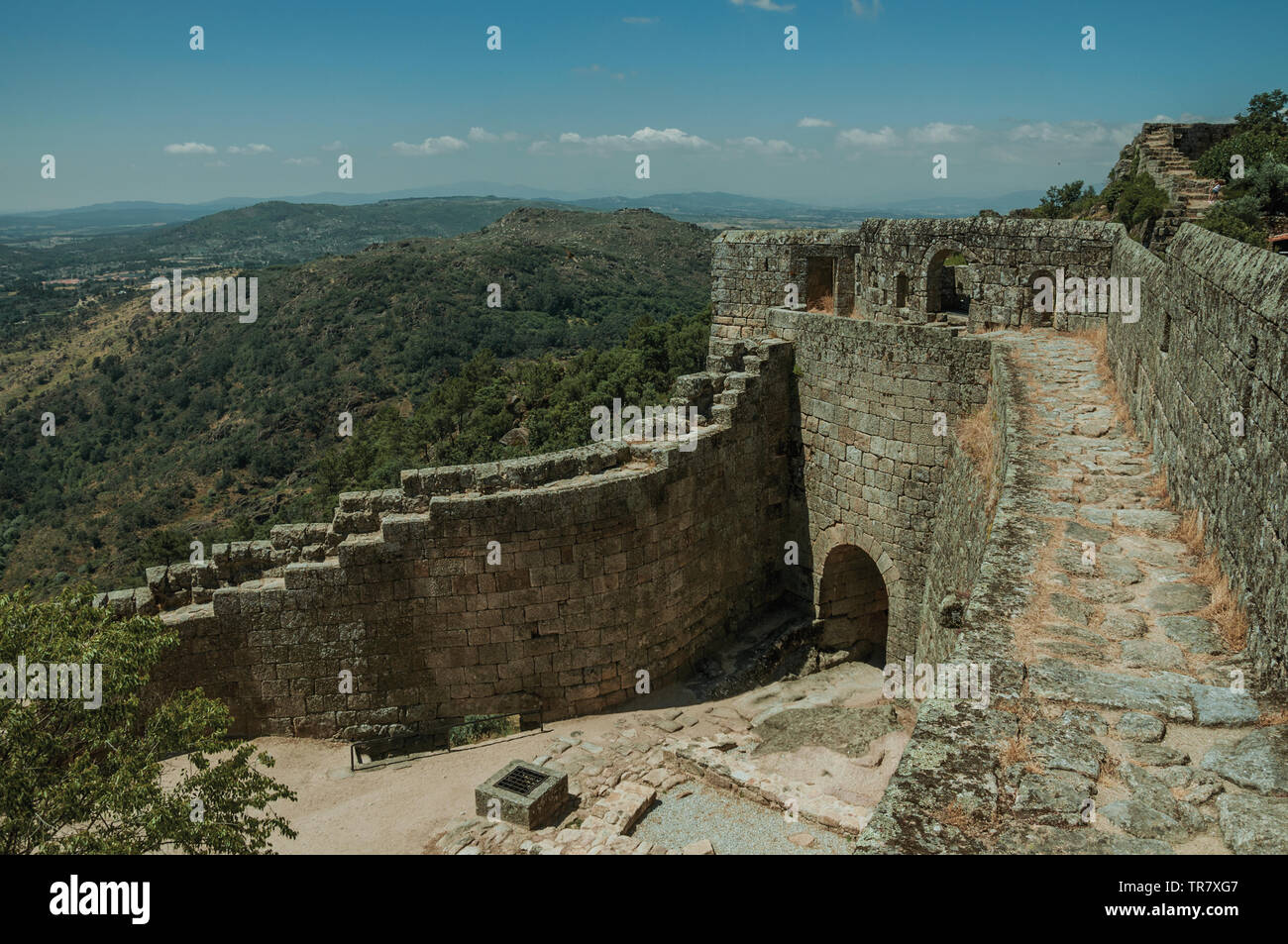 Pathway on stone wall with front gate and hilly landscape at the ...