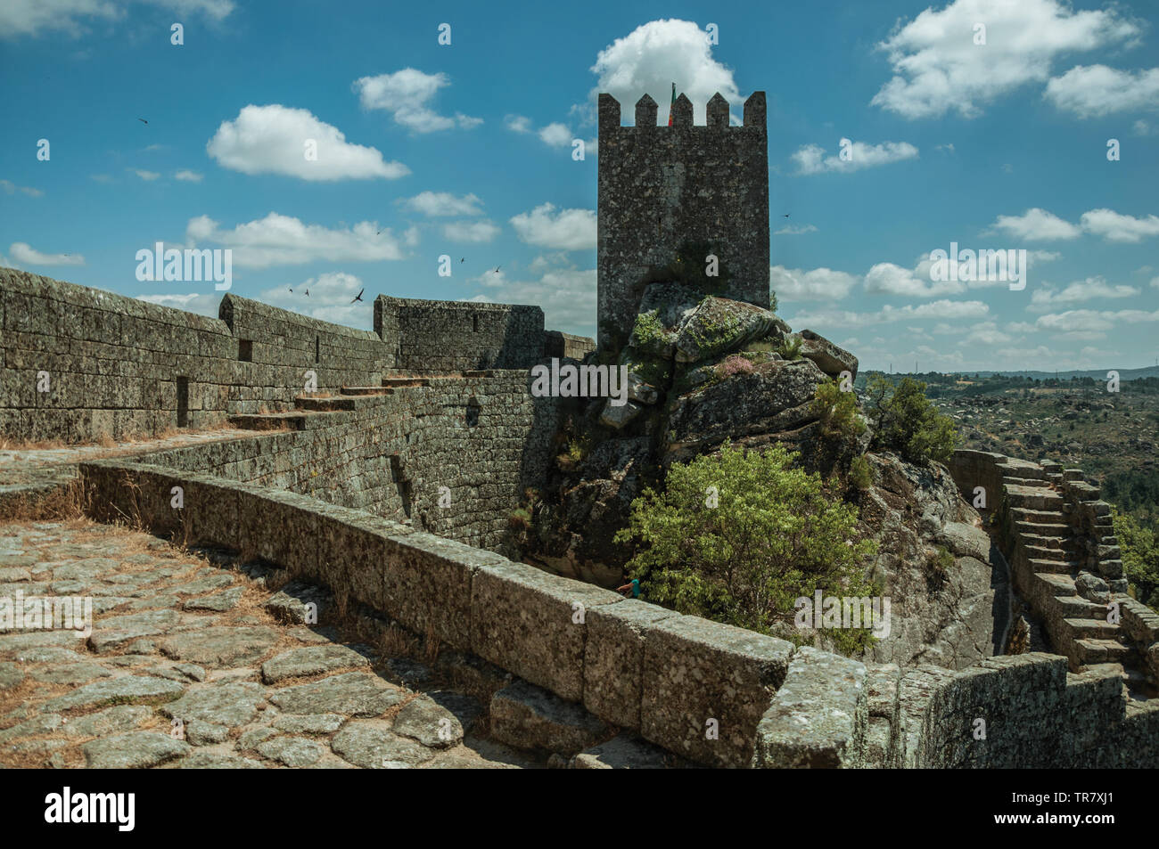 Pathway over stone wall with tower, in front of rocky courtyard at the ...