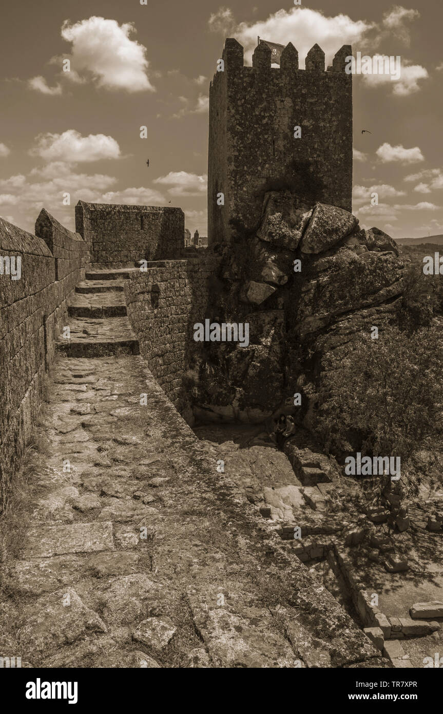 Pathway over stone wall with tower, in front of rocky courtyard at the ...