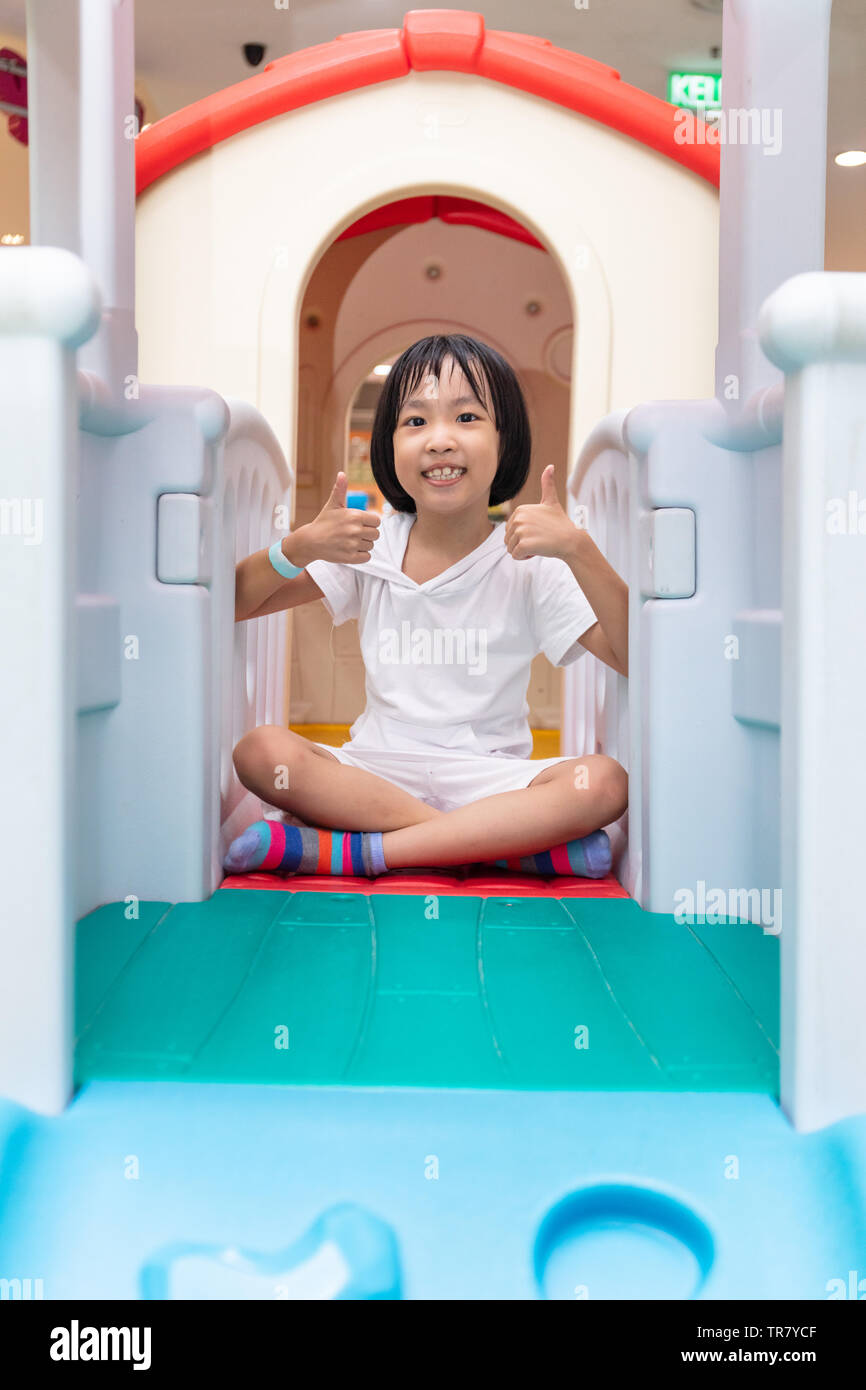 Asian Chinese little girl playing in toy house at indoor playground ...