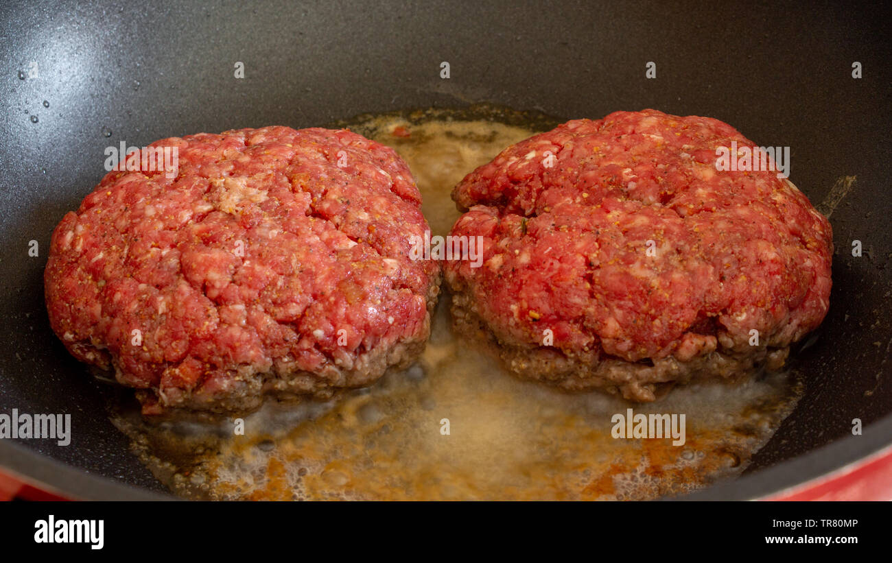 greasy burgers cooking in nonstick pan Stock Photo - Alamy
