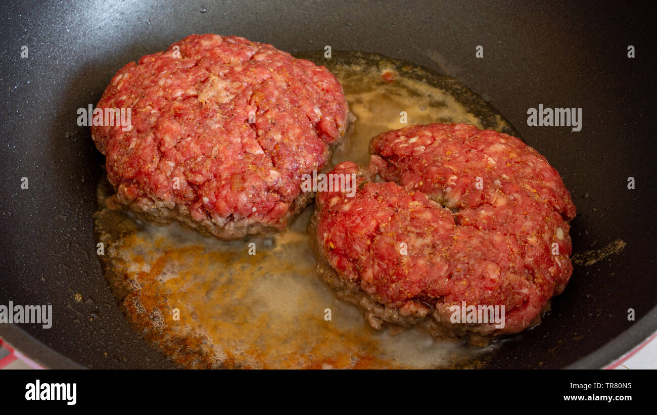 greasy burgers cooking in nonstick pan Stock Photo - Alamy