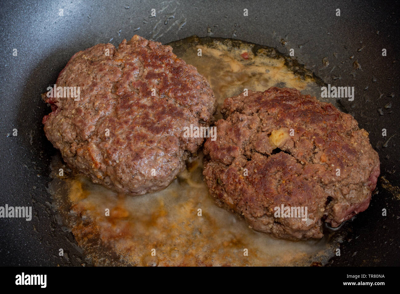 greasy burgers cooking in nonstick pan Stock Photo - Alamy