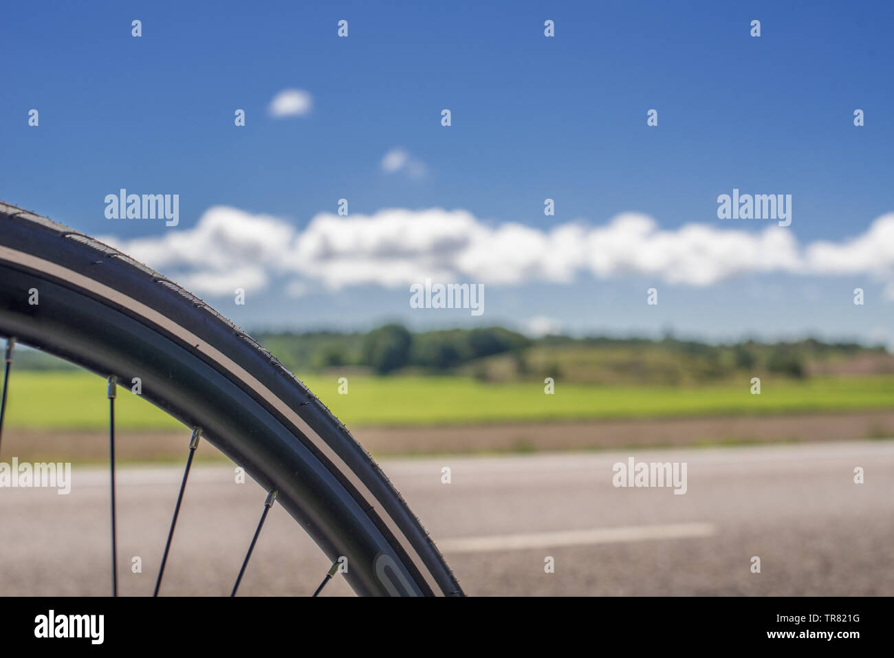 Bicycle wheel on a road in front of an open landscape Stock Photo - Alamy