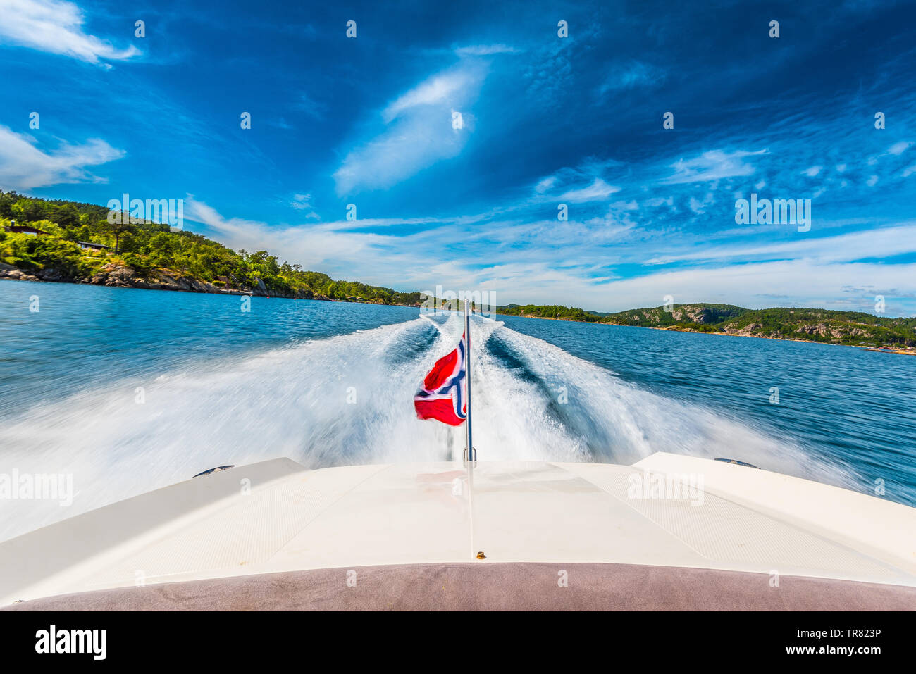 Speed boat swiftly crossing a sunny fjord in southern Norway sporting ...