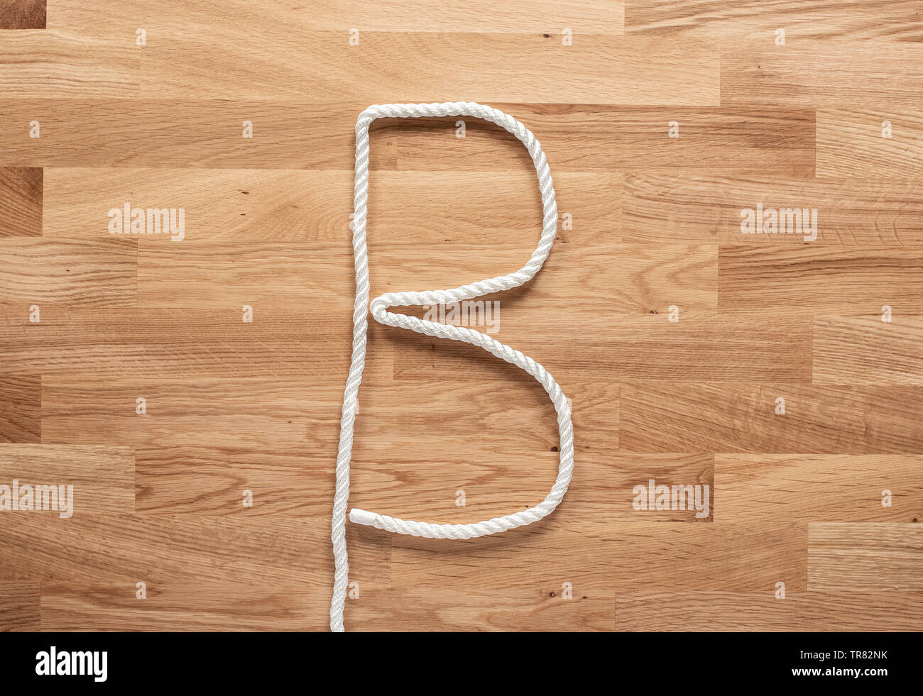 The letter B formed with white rope on a wooden table Stock Photo - Alamy