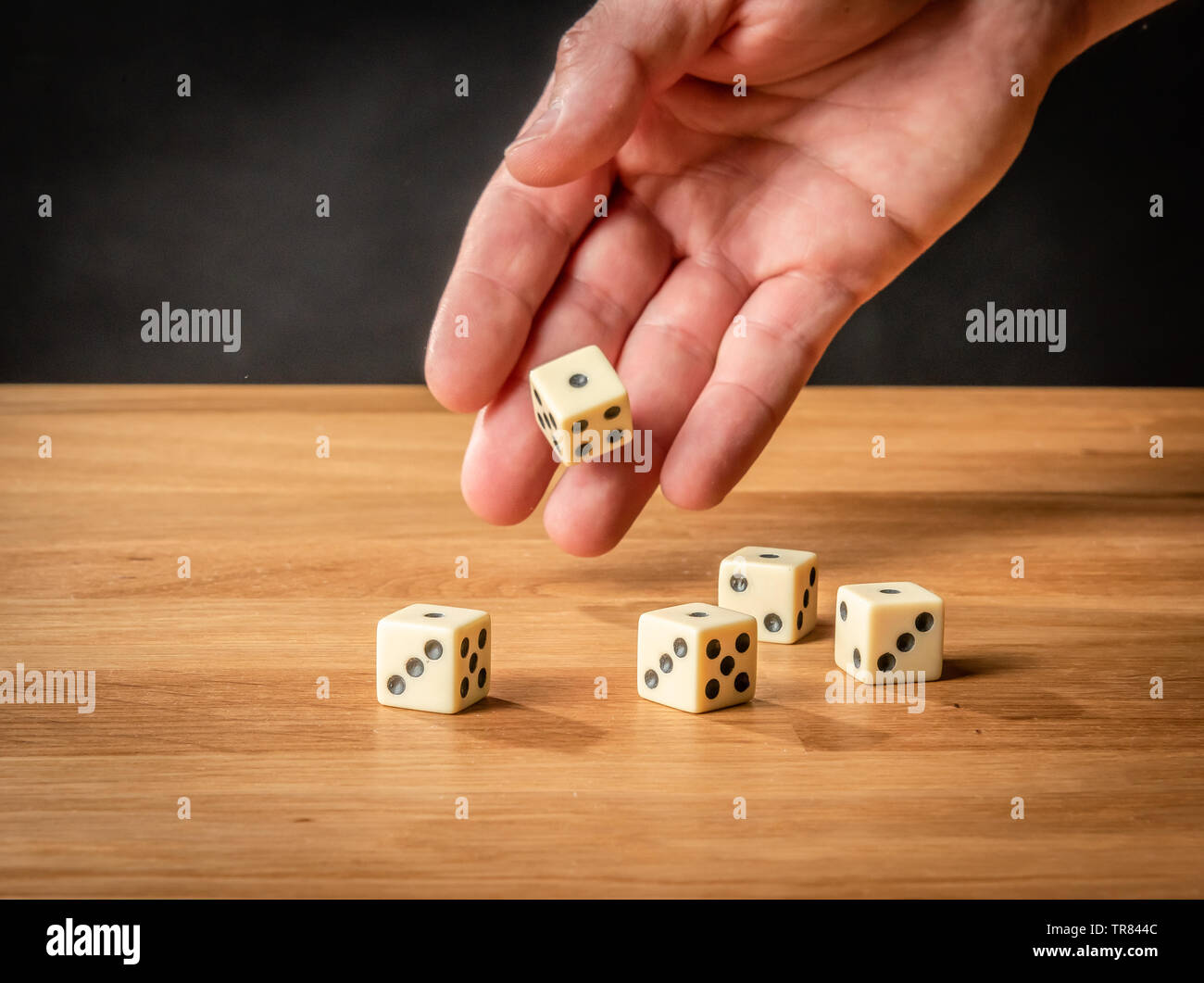 Hand throwing dice in front of a dark background Stock Photo - Alamy