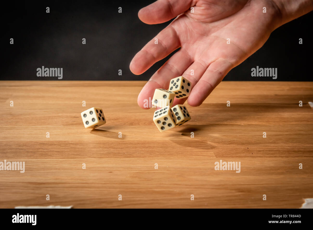 Hand throwing dice in front of a dark background Stock Photo - Alamy