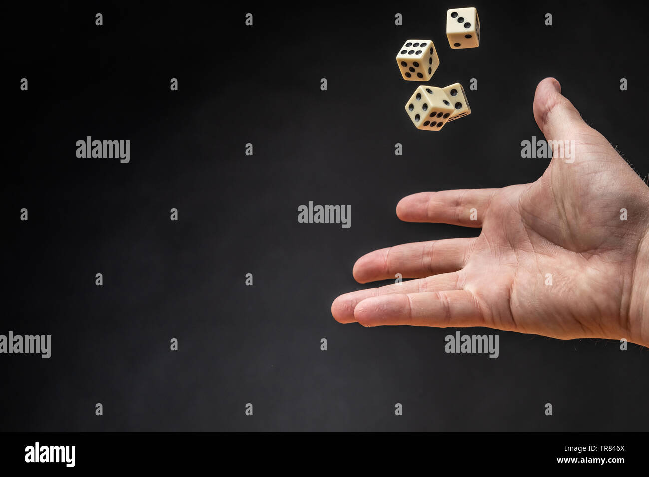 Hand throwing dice in front of a dark background Stock Photo - Alamy