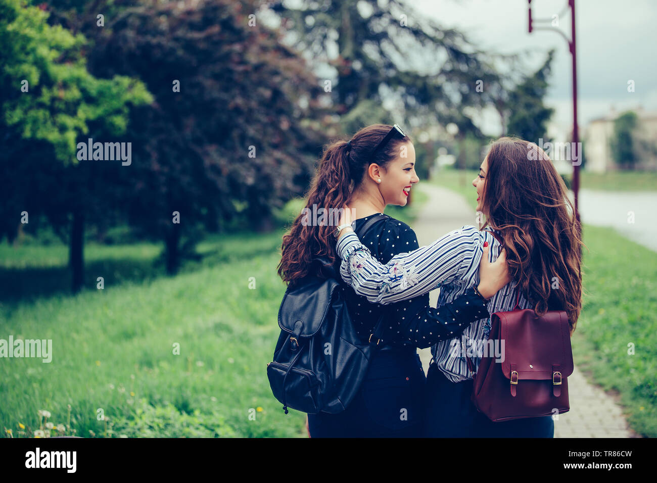 Back view of a two beautiful female friends hugging each other while ...