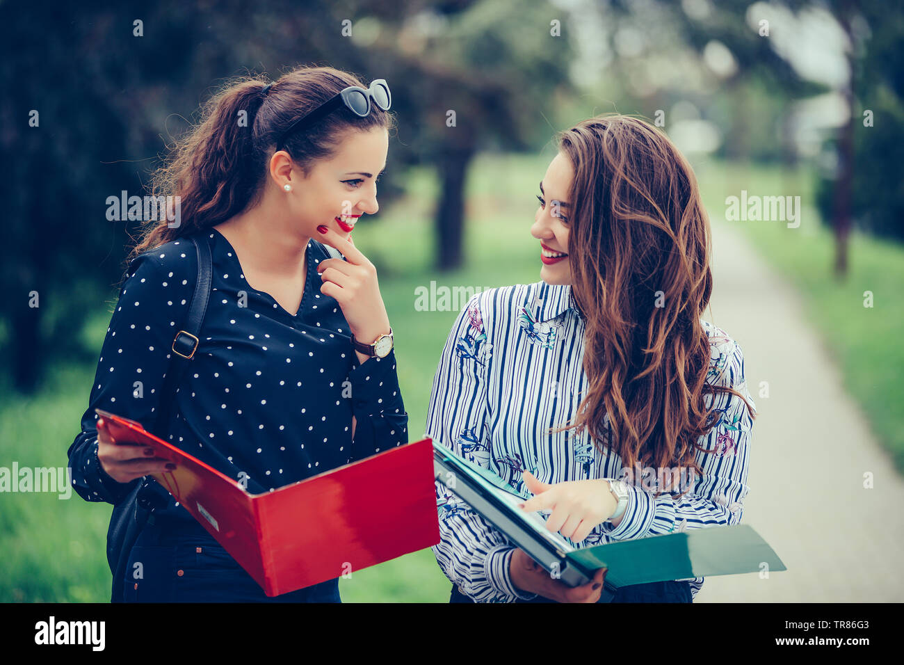 Two beautiful female friends, students checking paper notes before exam ...
