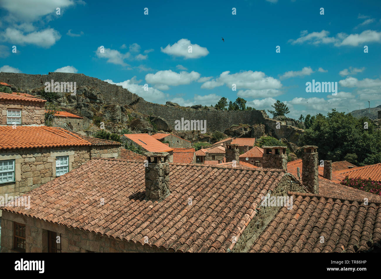 Rooftops of stone old houses with chimneys and large wall on background ...