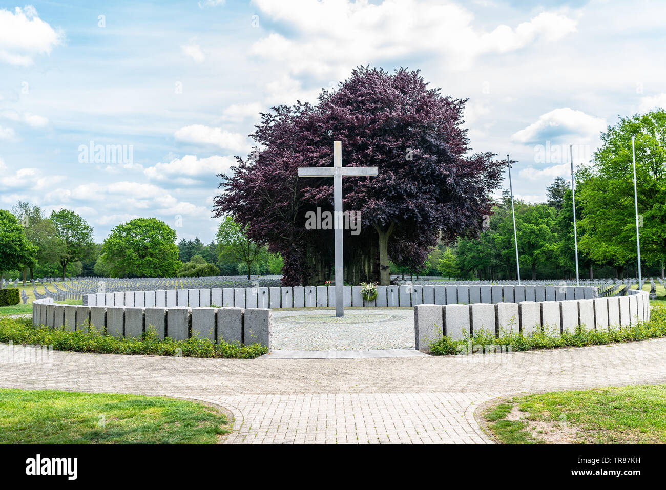 A large concrete cross on a cemetery against a blue sky with white ...