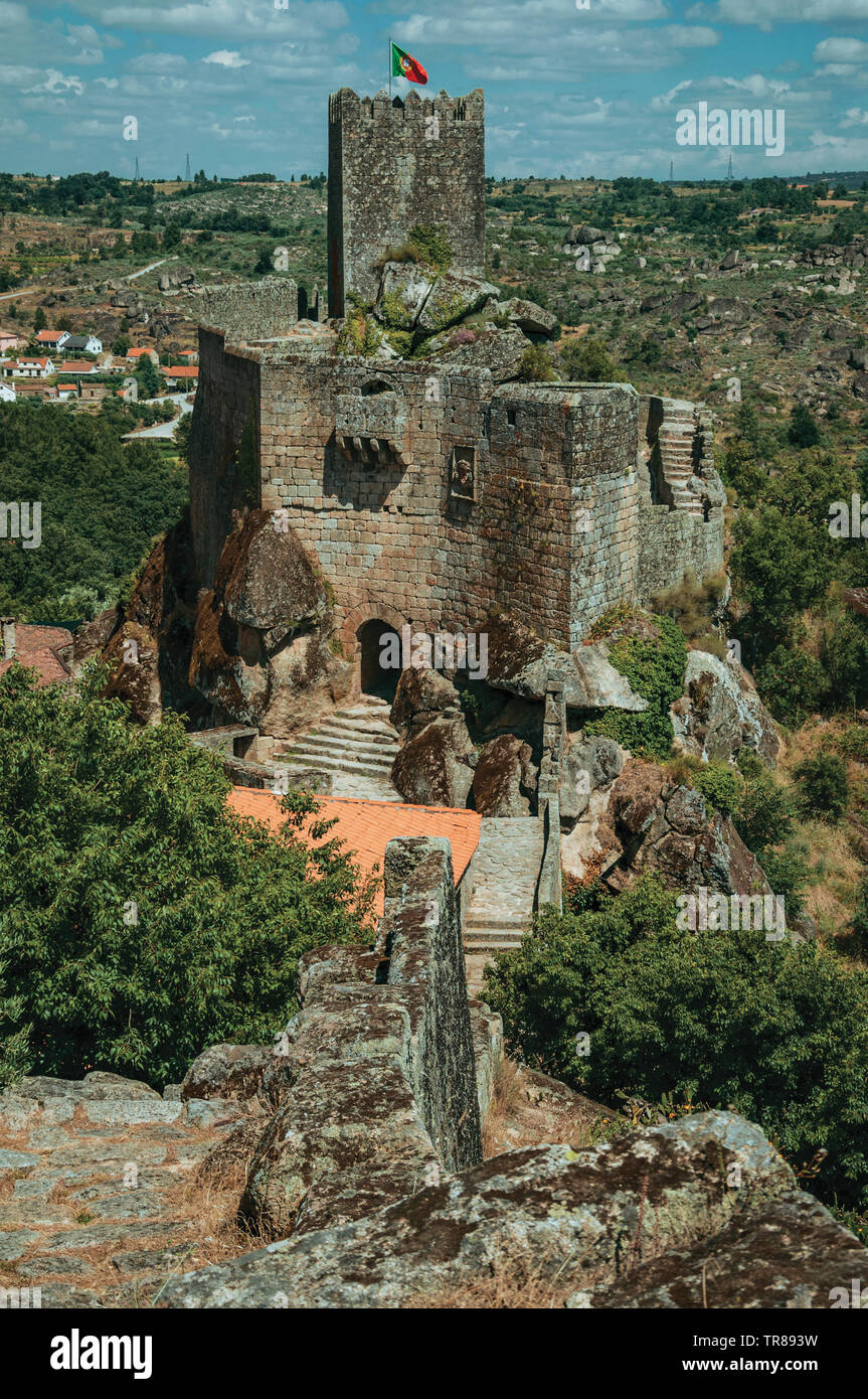 Stone Castle with tower over cliff and hilly landscape with roof houses ...