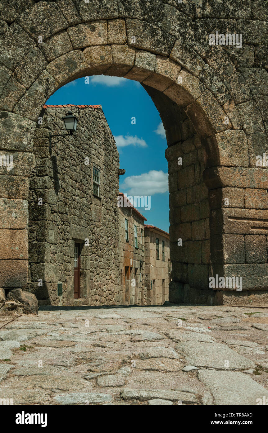 Old house on deserted alley seen through arch gate from a stone wall at ...