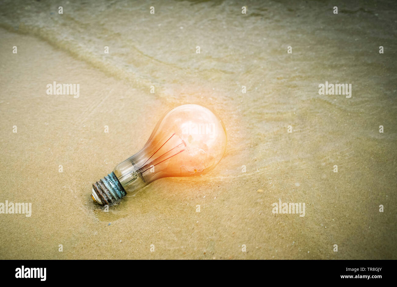 Idea concept light bulb on beach with orange lighting on sand / garbage ...