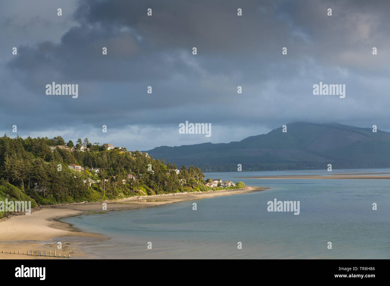 Light from sunset spotlights homes and a golden sandy beach along a ...