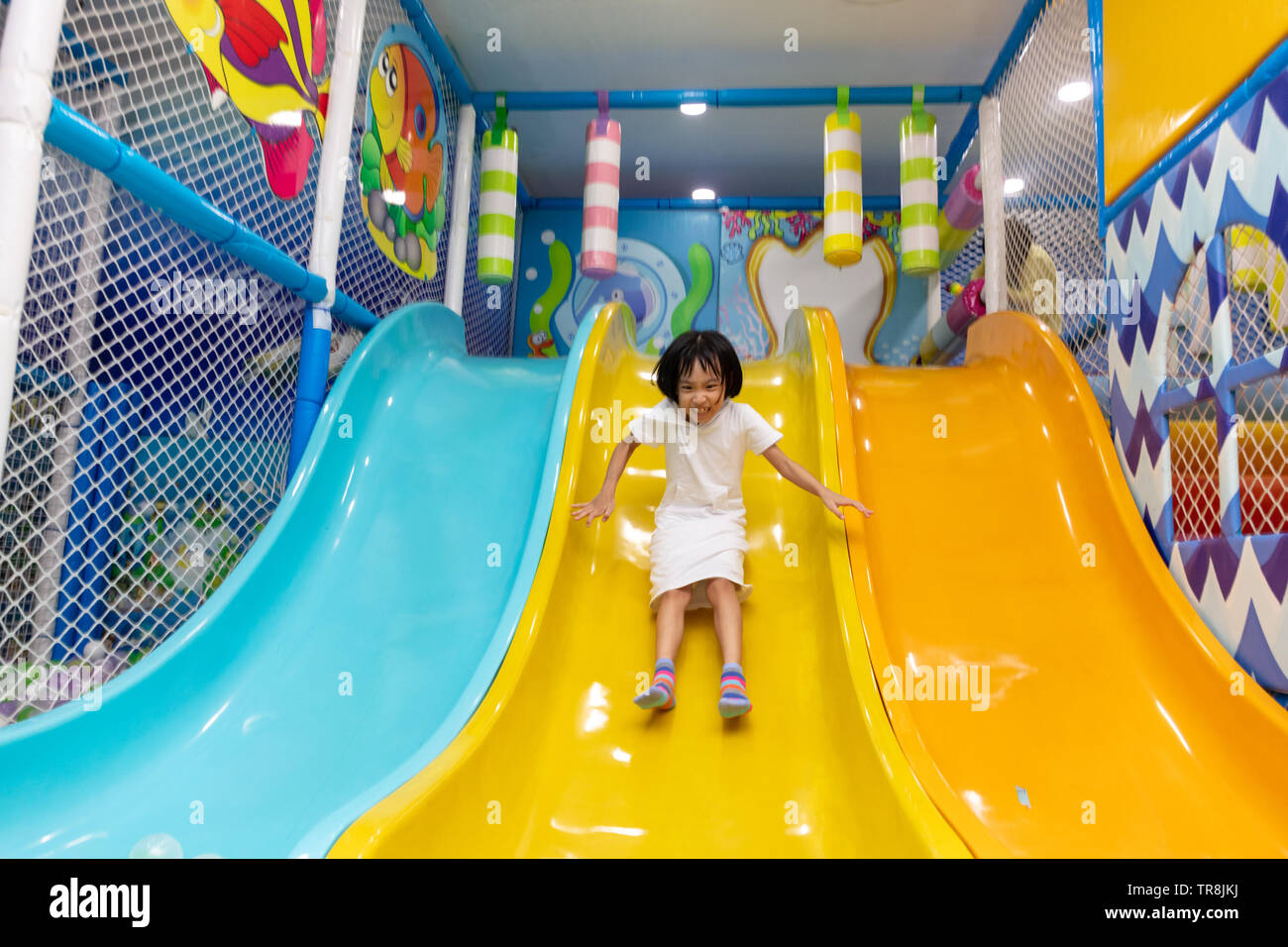 Asian Chinese little girl playing on the slide at indoor playground ...