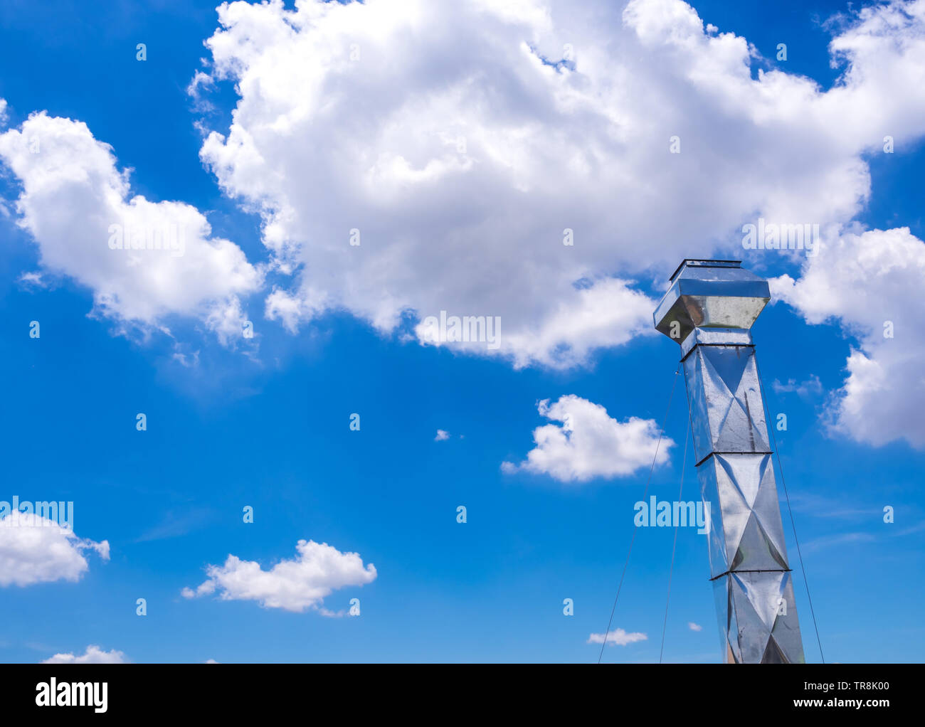Shiny steel smokestack and cloud in blue sky Stock Photo - Alamy