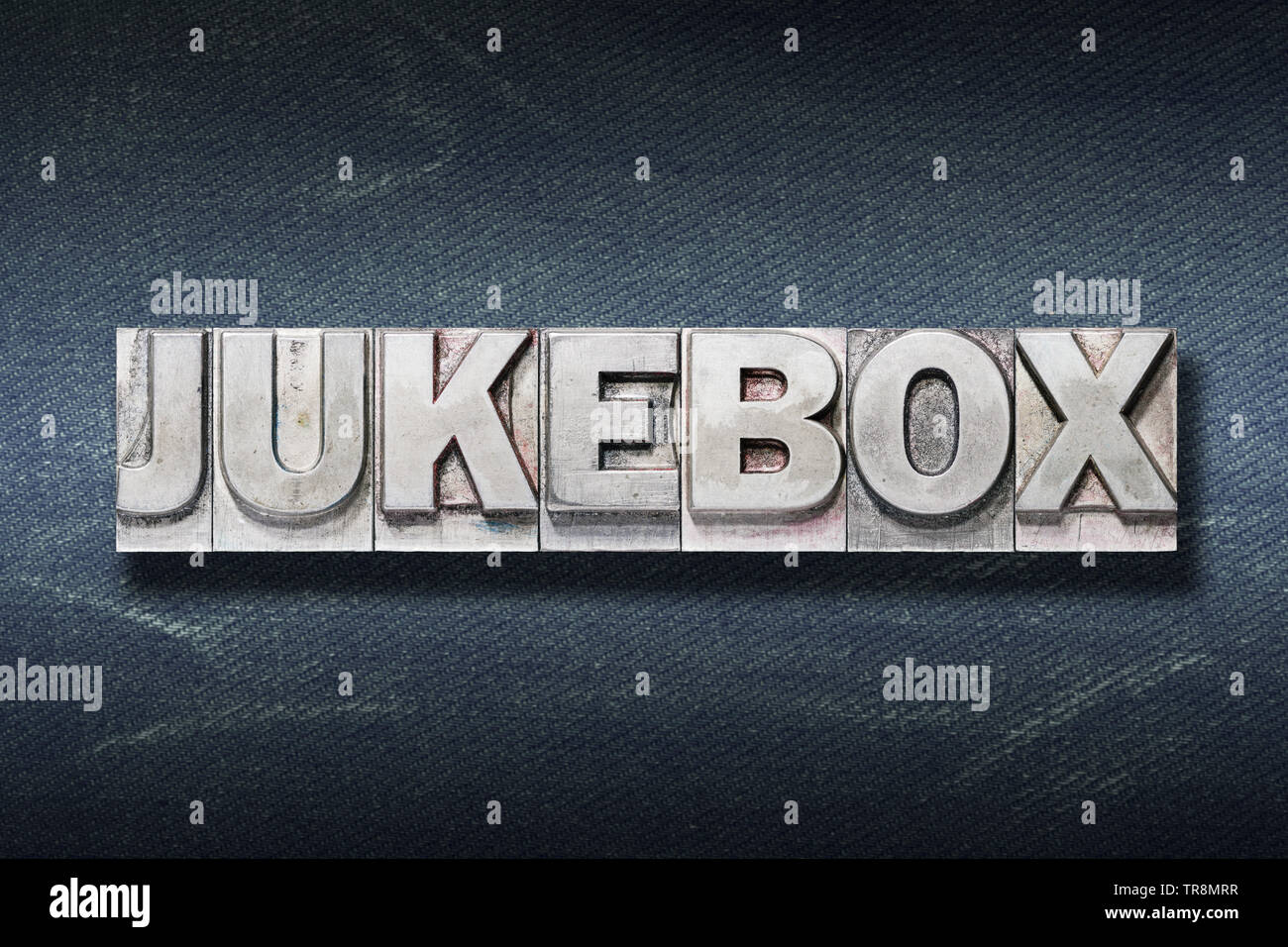 jukebox word made from metallic letterpress on dark jeans background ...
