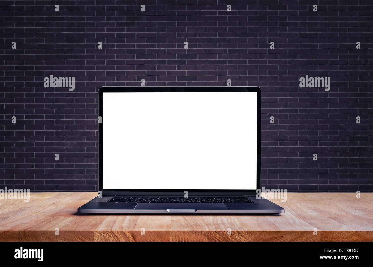 Modern computer,laptop with blank screen on table and brick wall ...