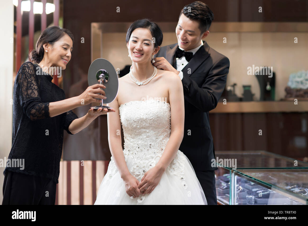 Happy bride trying on pearl necklace in jewelry store Stock Photo - Alamy