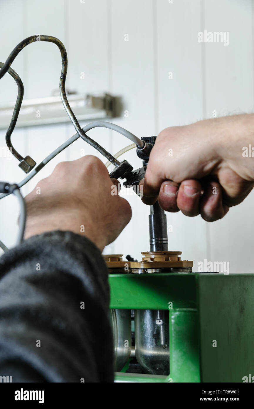 Mechanics a repairing a diesel injector. Worker's hands install ...