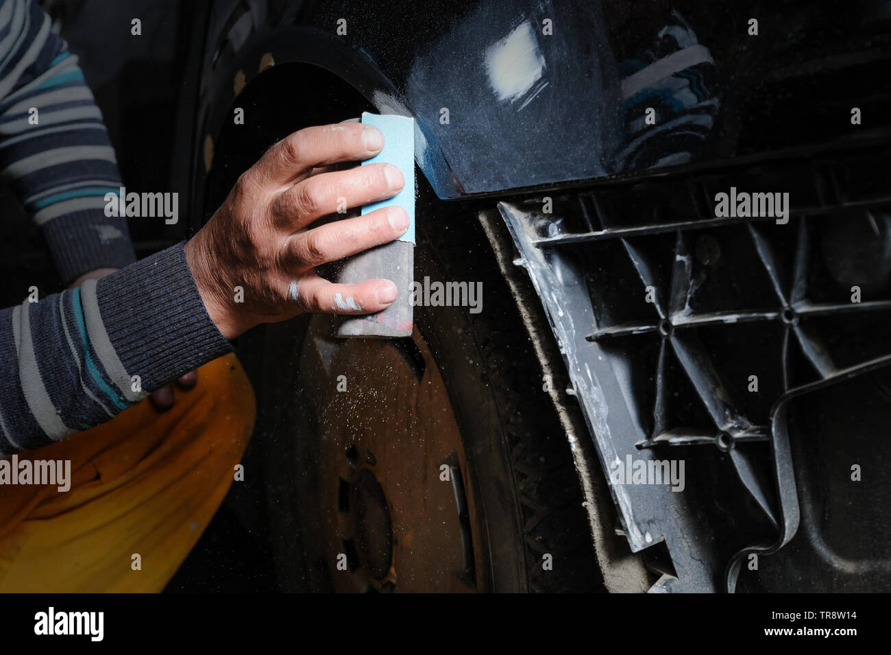 Car body repair. A fitter is fixing a dents on a car. Man's hand is ...