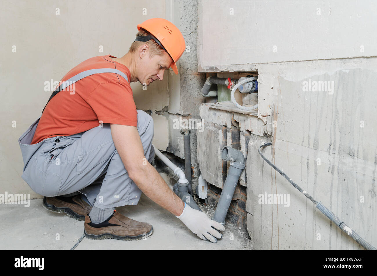 Worker is installing sewer pipes in a kitchen of a apartment Stock ...
