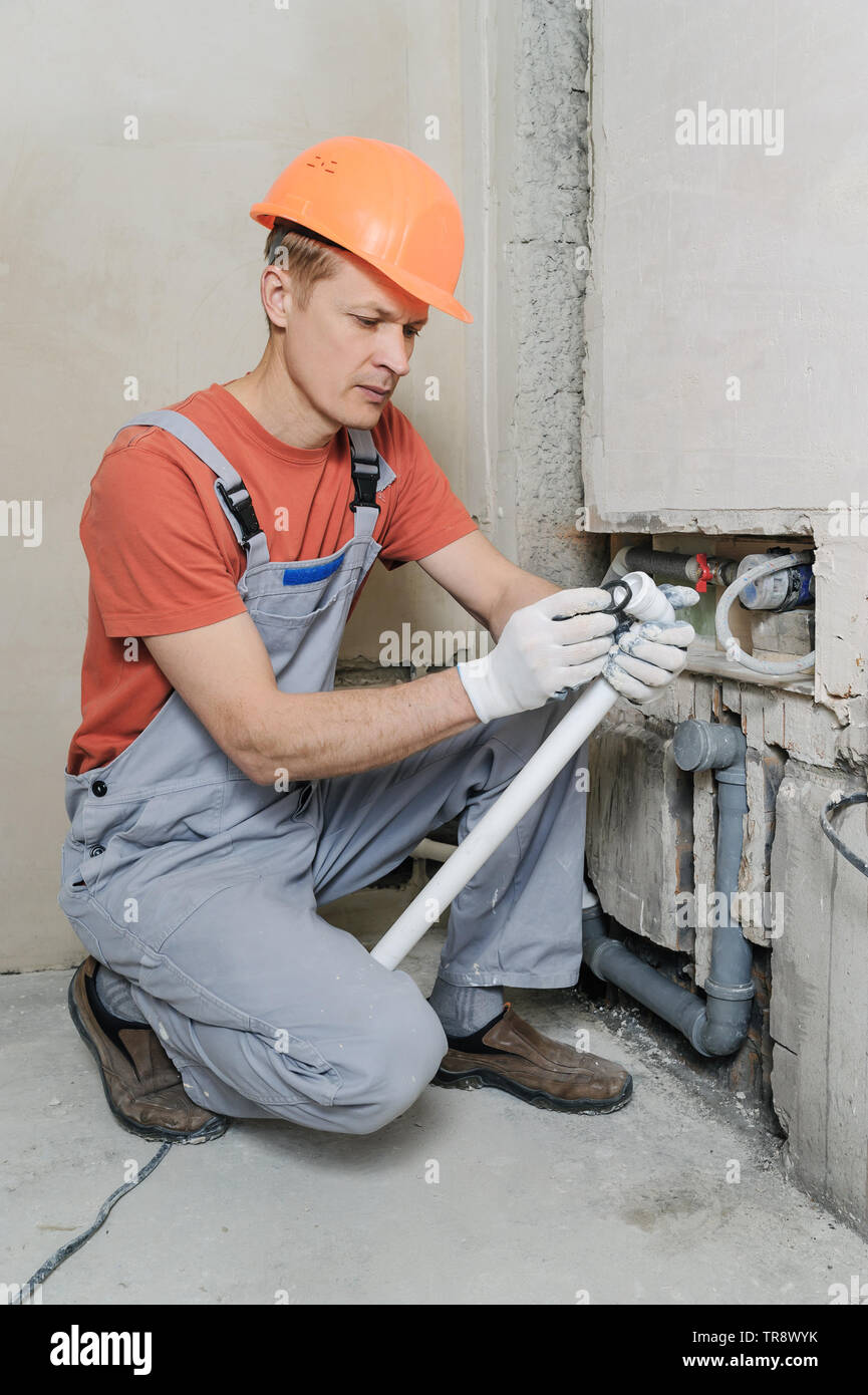 Worker is installing sewer pipes in a kitchen of a apartment Stock ...