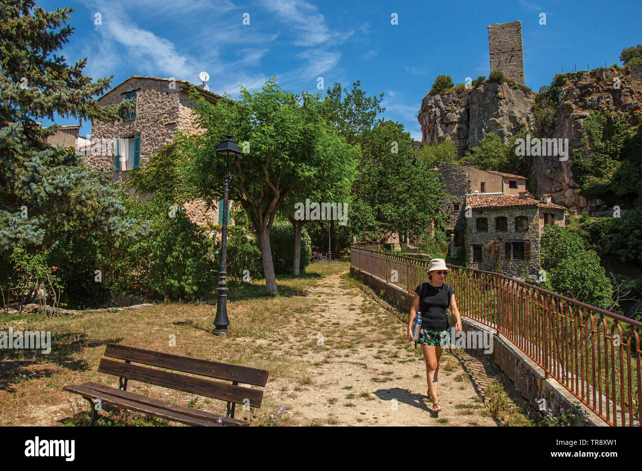 Woman in a garden with trees, houses and cliff in Chateaudouble ...