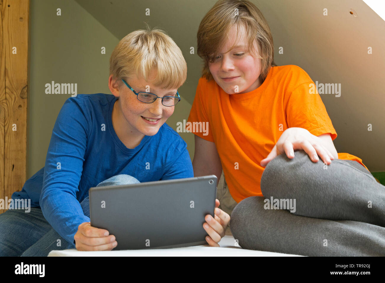 boy plyaing with tablet computer, his friend watching, Germany Stock ...