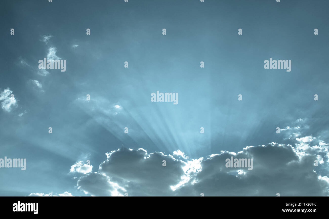 Stark and cold blue sky with sun rays from behind a winters cloud image ...