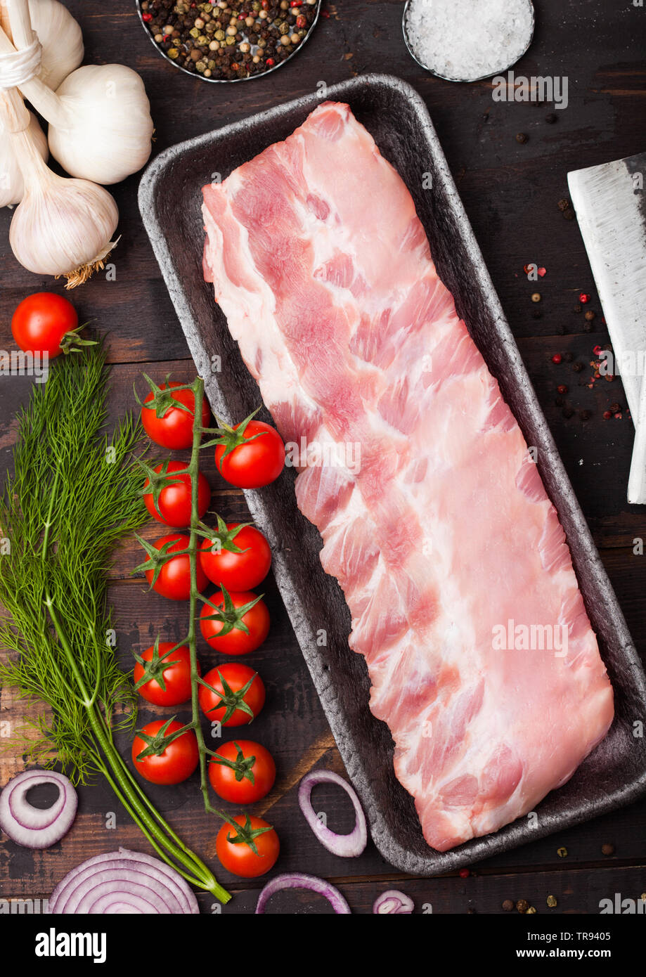 Plastic tray with raw pork ribs on chopping board and vintage meat fork ...