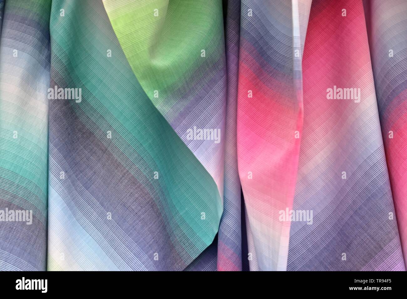 Close up surface of colorful fabrics cloth and textiles being folded ...