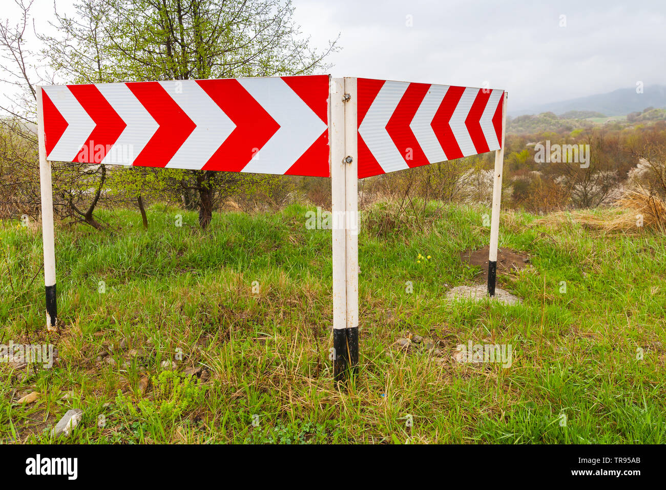 Dangerous turns. Red and white striped arrows. Road sign mounted on a ...