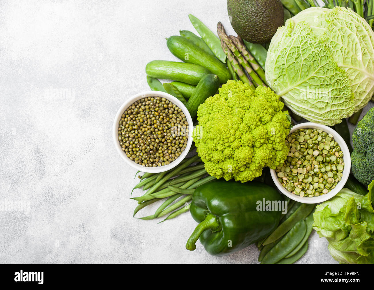 Assorted green toned raw organic vegetables on white background ...