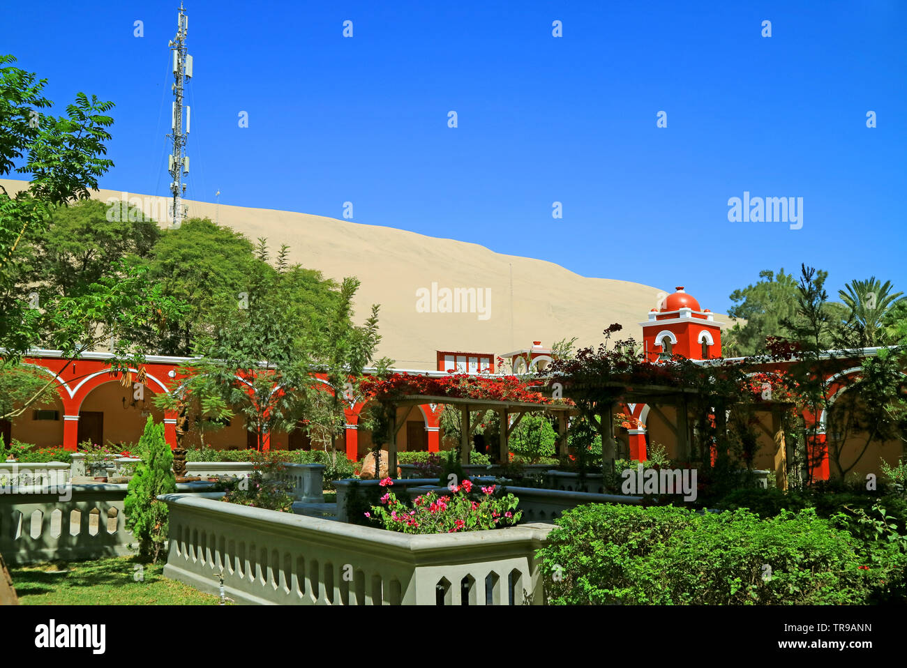 Red tower of vintage Peruvian building against the sand dunes of ...