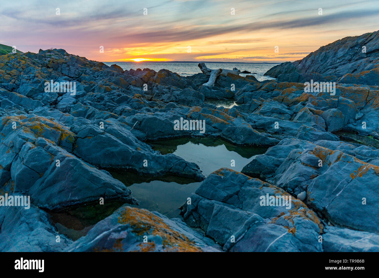 Rock pools and a cloudy sunset over the ocean Stock Photo - Alamy