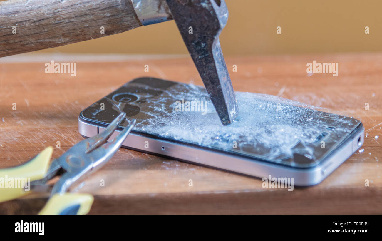 Abstract photo. A Hammer and a smartphone with a broken screen. Cracked ...