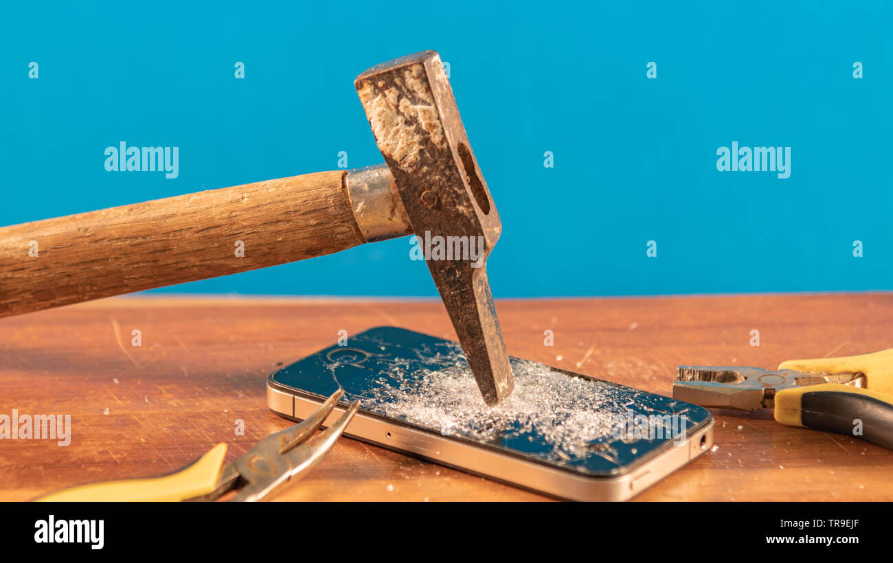 Abstract photo. A Hammer and a smartphone with a broken screen. Cracked ...