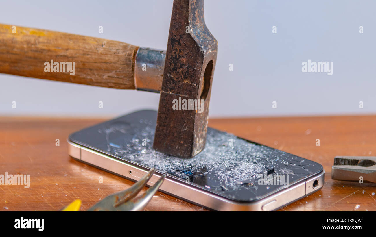 An old hammer and smartphone. With broken screen on a white background ...