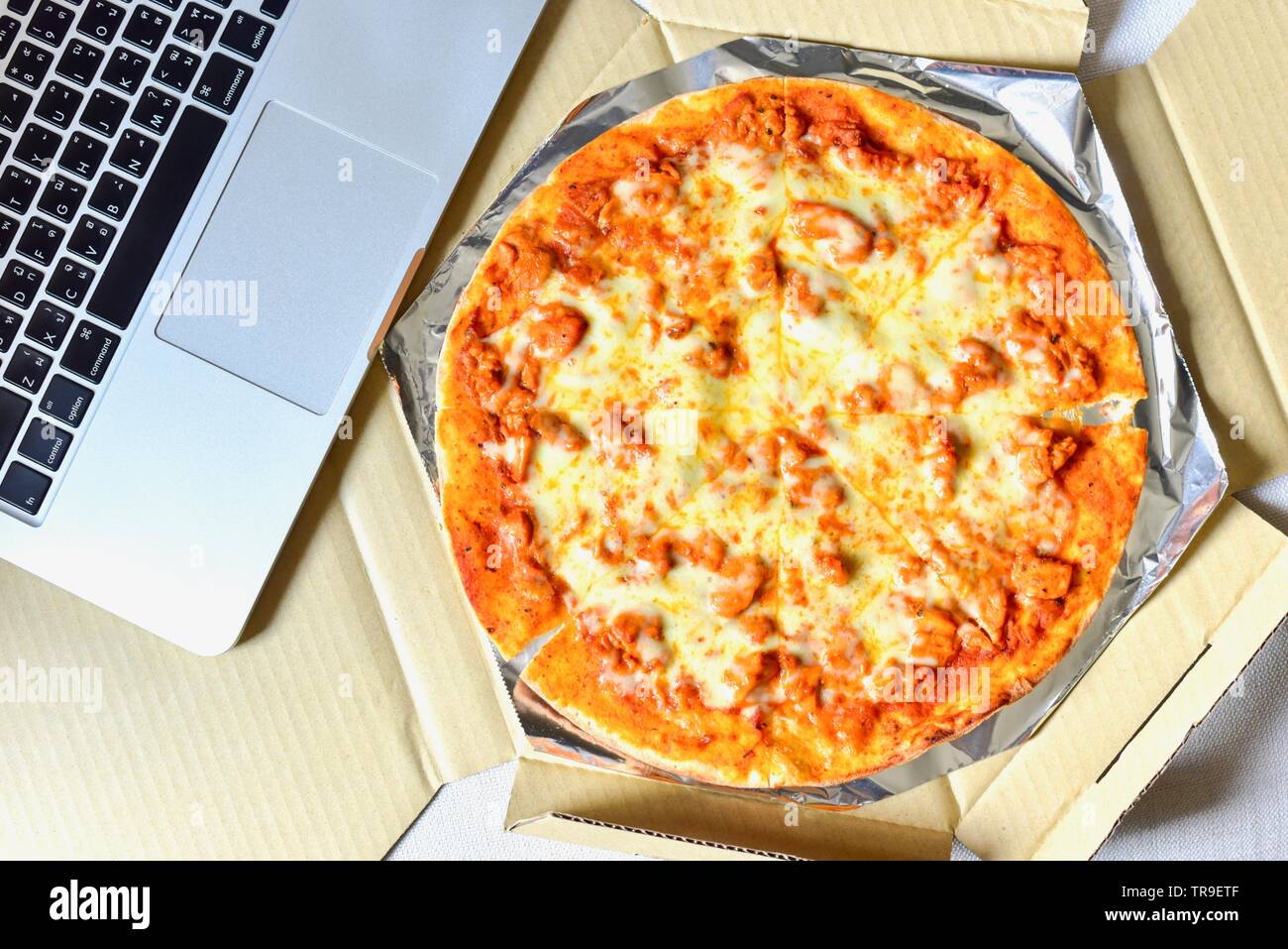 Box of Butter Chicken Pizza and Laptop Stock Photo - Alamy