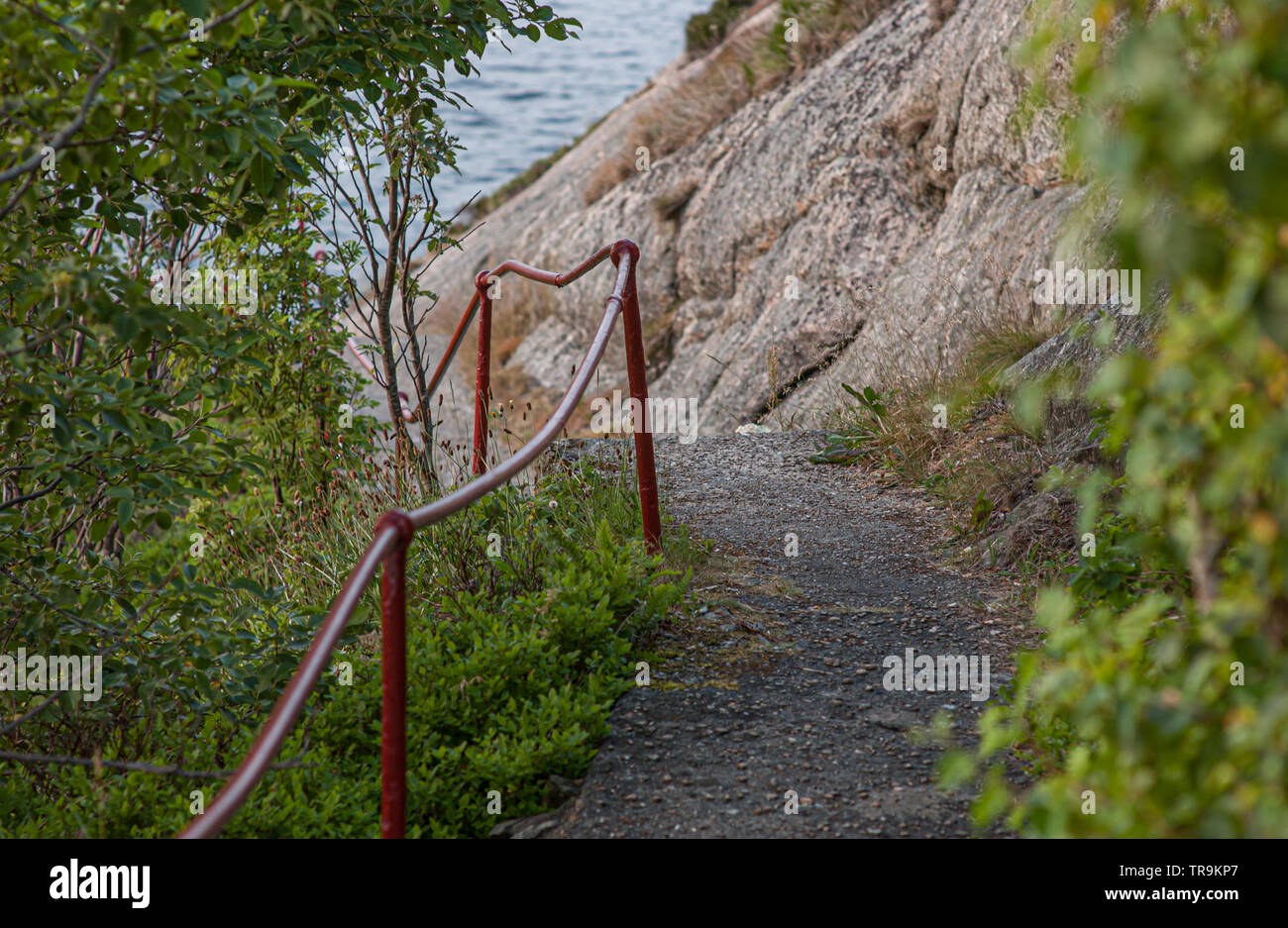 Red metal hand rails by a path down some cliffs Stock Photo - Alamy