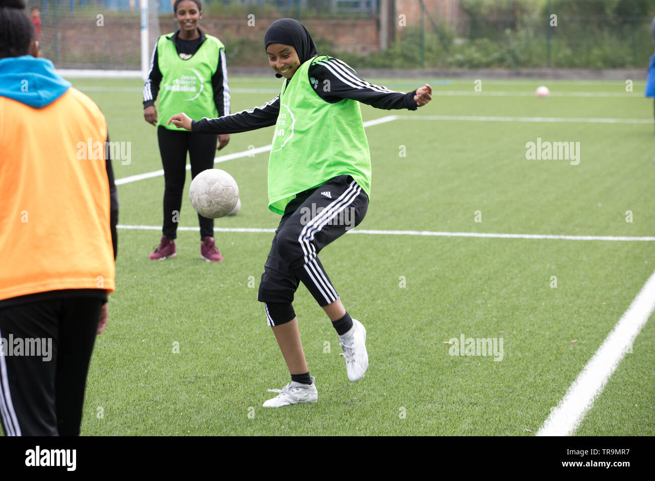 Muslim girls playing football on an astroturf training pitch. Some are ...