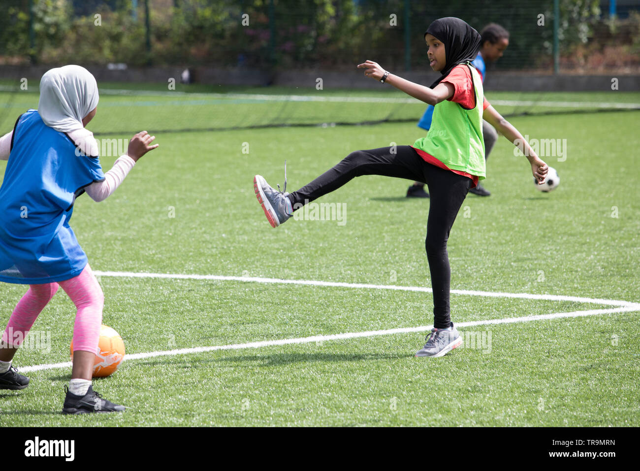 Muslim girls playing football on an astroturf training pitch. Some are ...