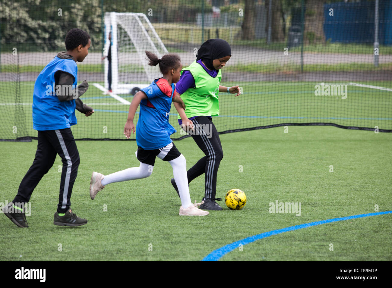 Muslim girls playing football on an astroturf training pitch. Some are ...