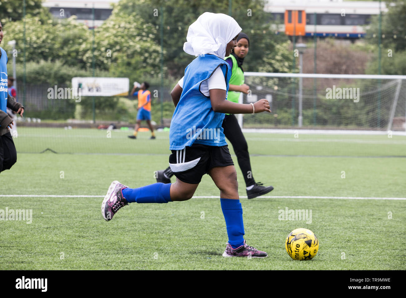 Muslim girls playing football on an astroturf training pitch. Some are ...