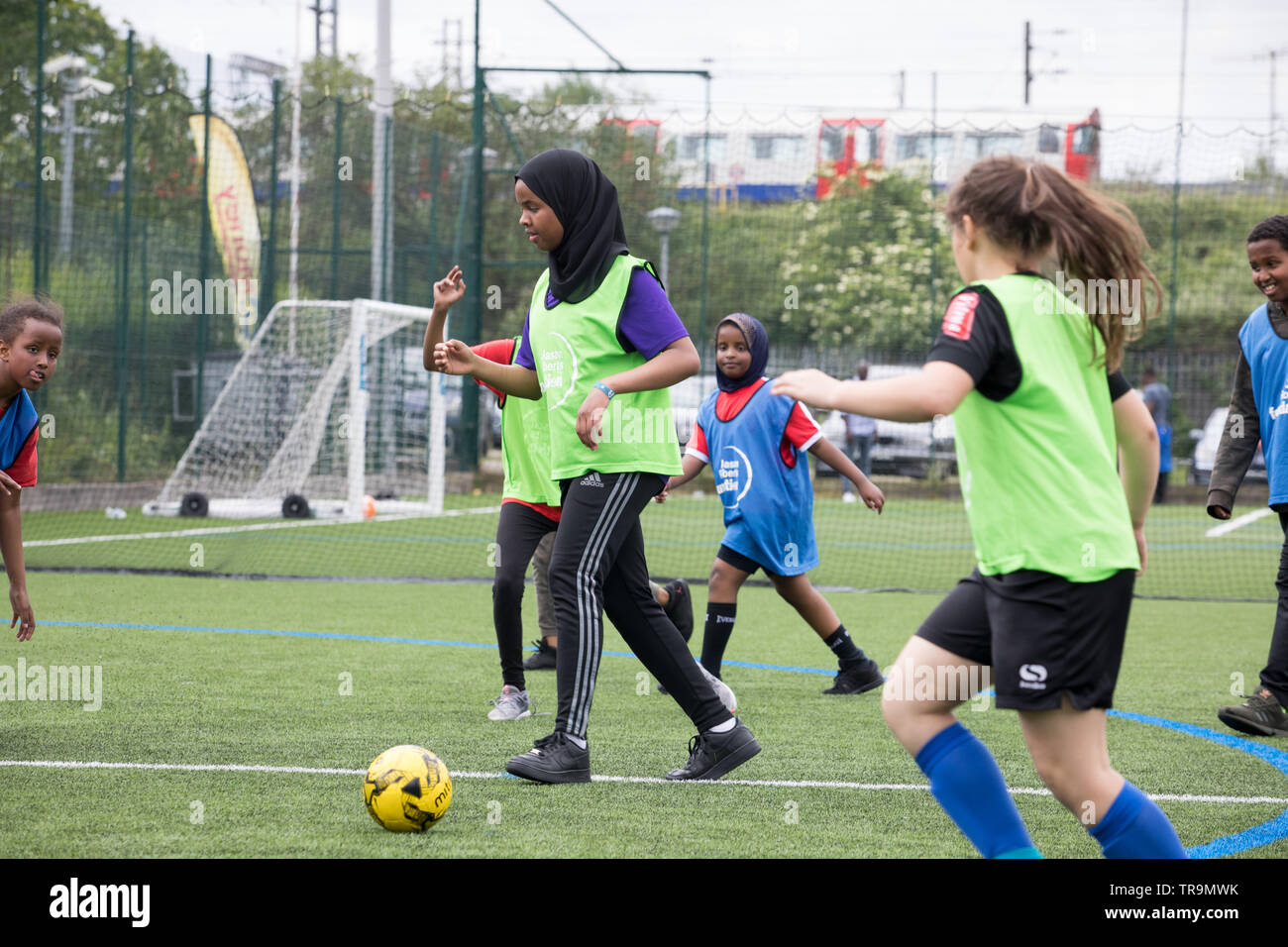 Muslim girls playing football on an astroturf training pitch. Some are ...